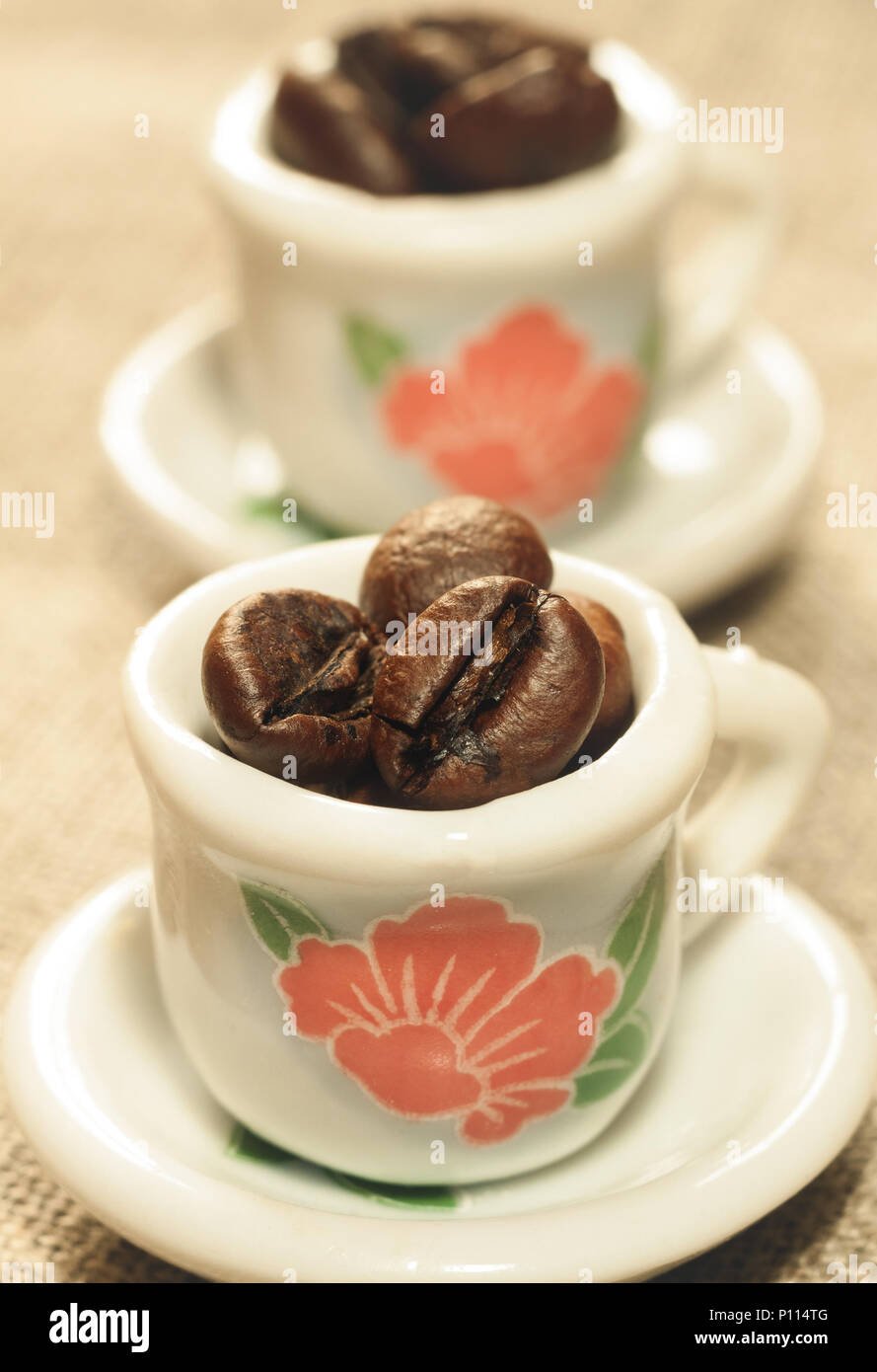 Coffee beans in a small lovely porcelain cups close-up. Strong coffee ...