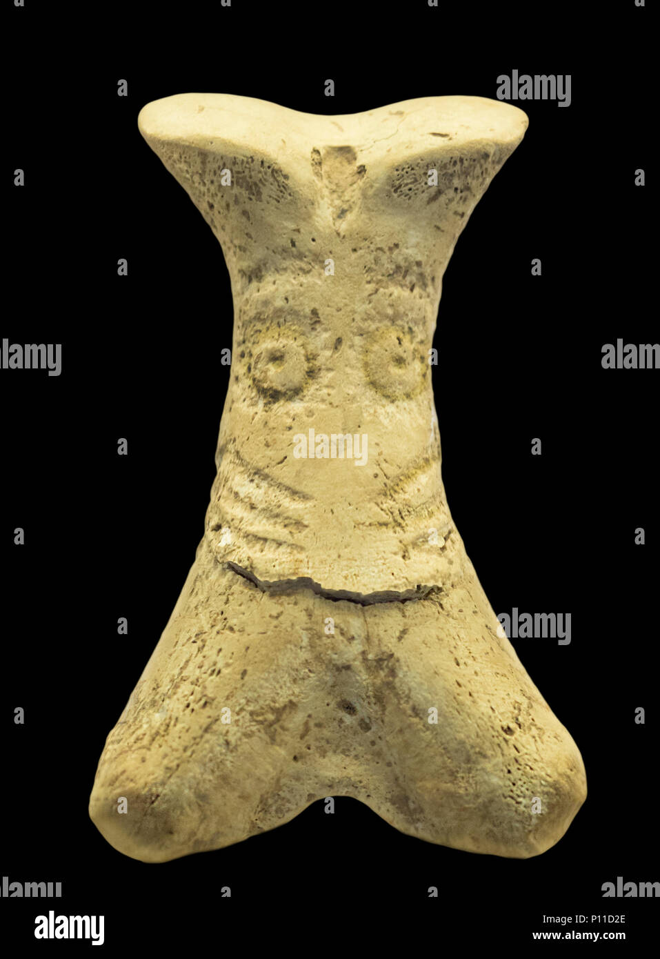 Phalanx bone idol with face depicted. Front view. Isolated over black ...