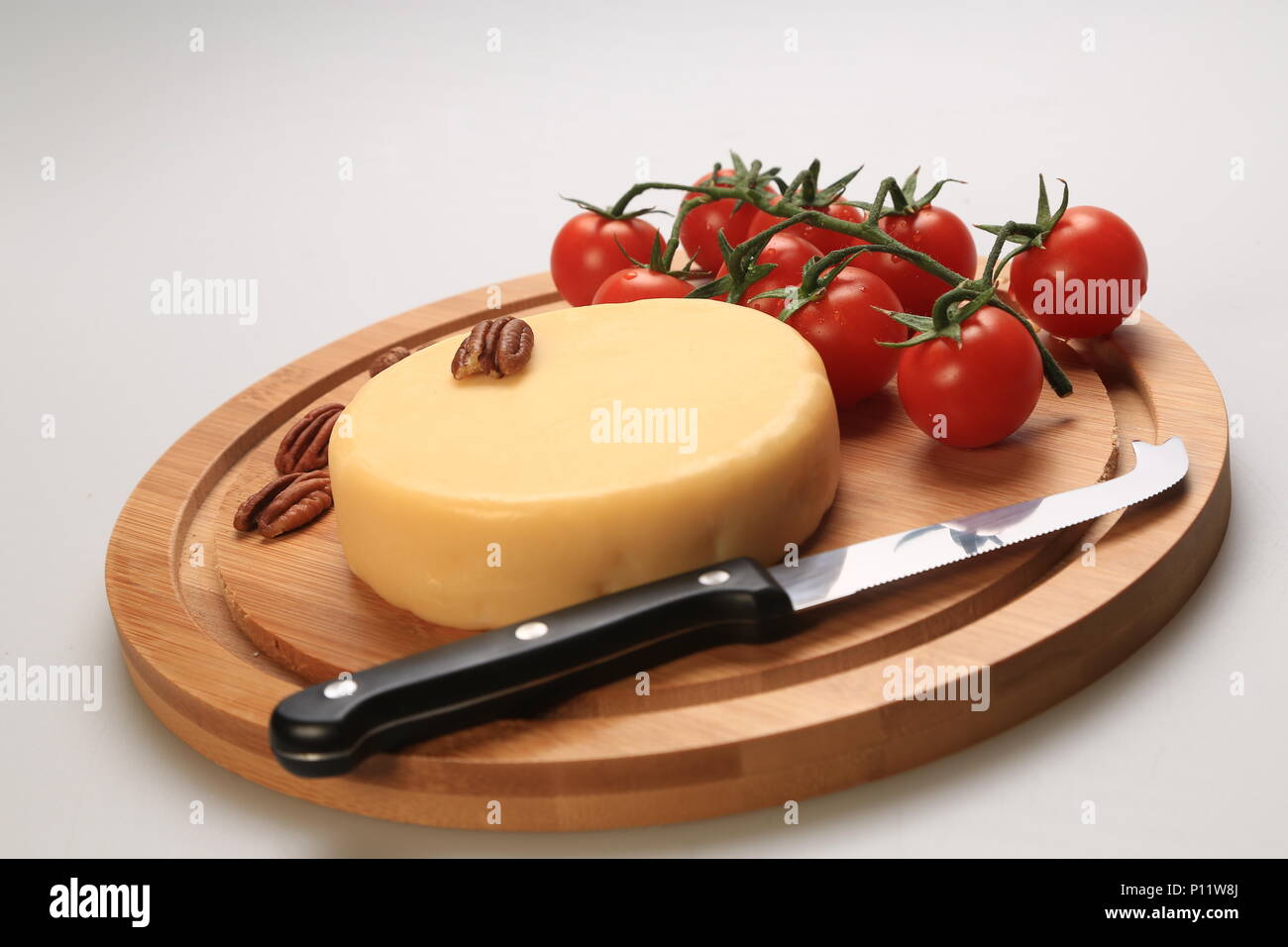 Small cheese wheel next to cherry tomatoes Stock Photo - Alamy