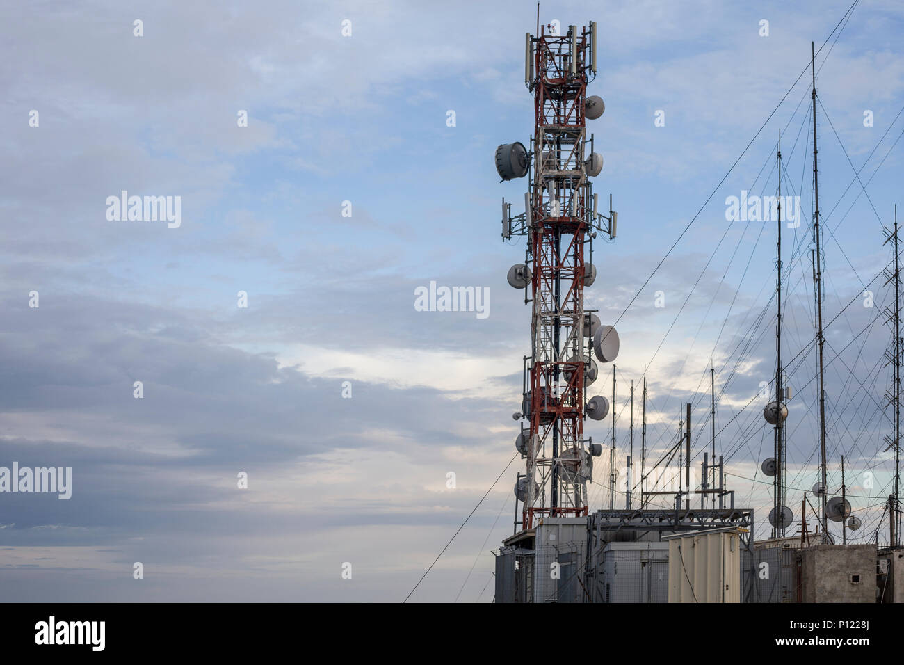 Telecom tower holding multiple antennas kept near to multiple panel boxes. There are cable ...