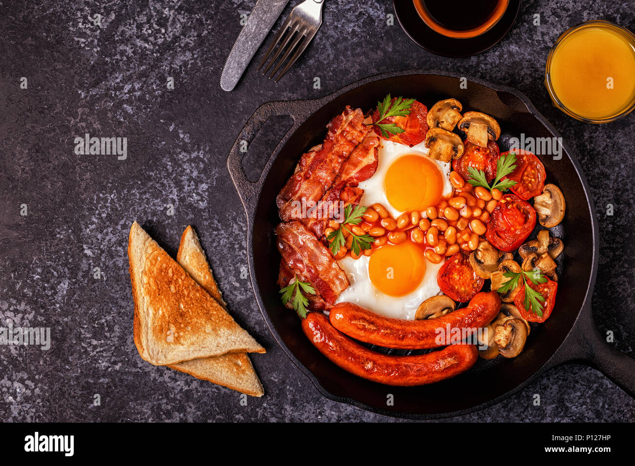 Traditional full English breakfast with fried eggs, sausages, beans ...