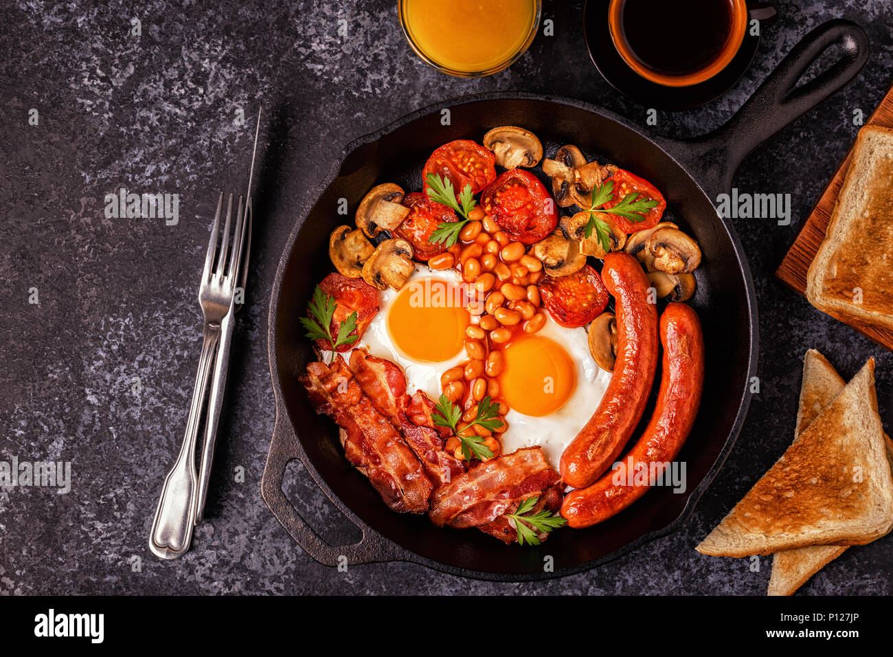 Traditional full English breakfast with fried eggs, sausages, beans ...