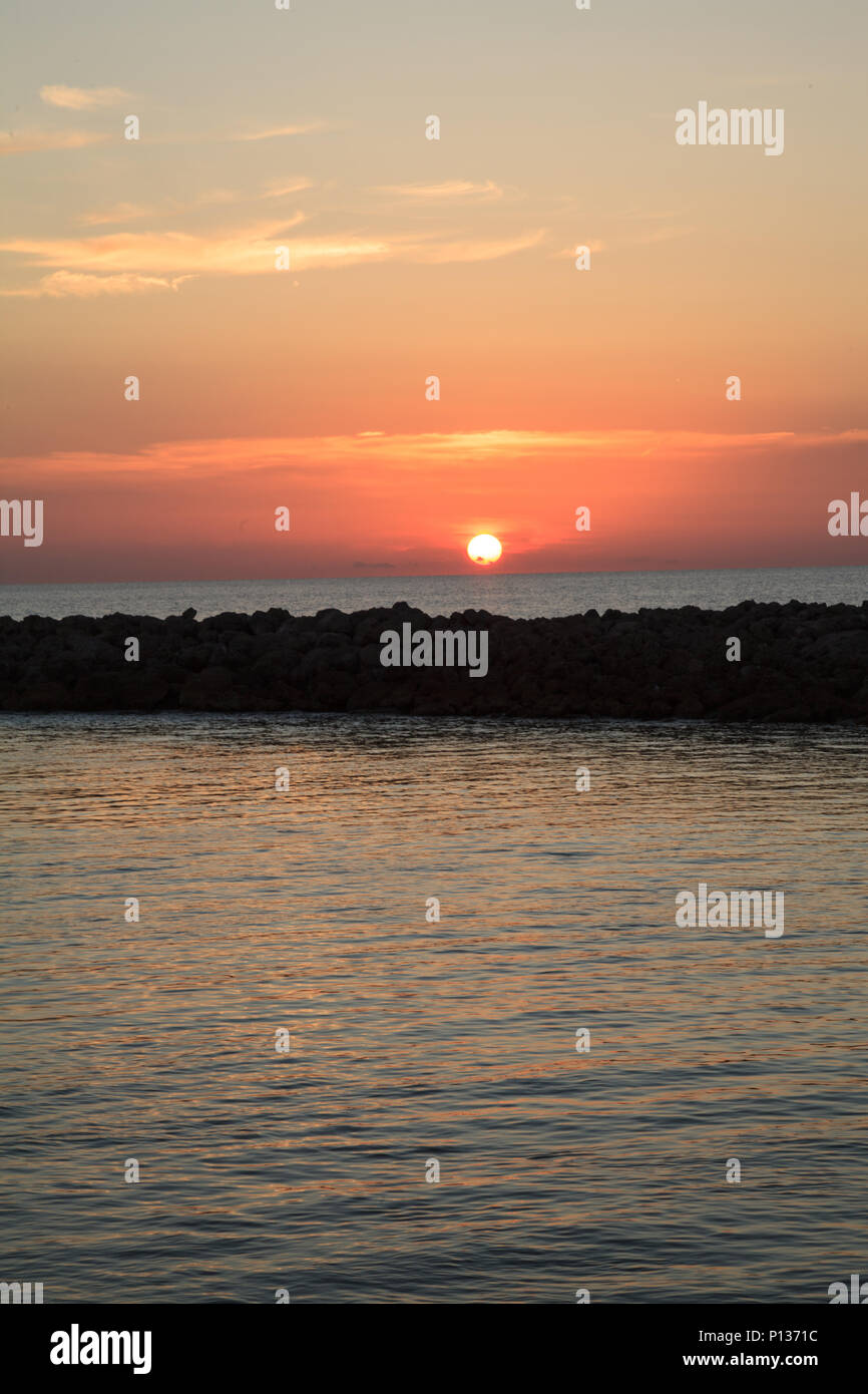 Orange and red sun over a jetty at Doctors Pass river near Lowdermilk ...