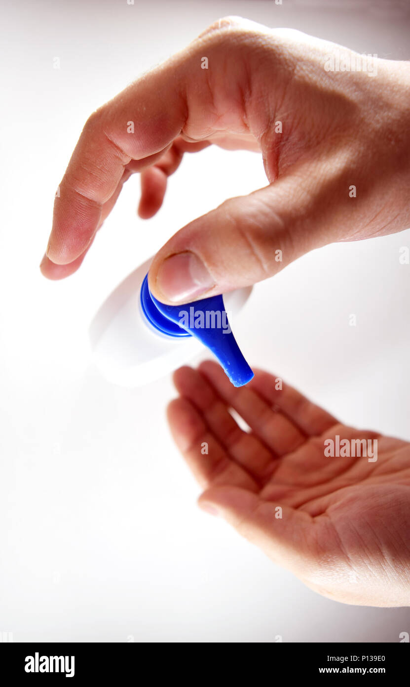 Hand pumping moisturizing lotion or face cleaner from white bottle with ...