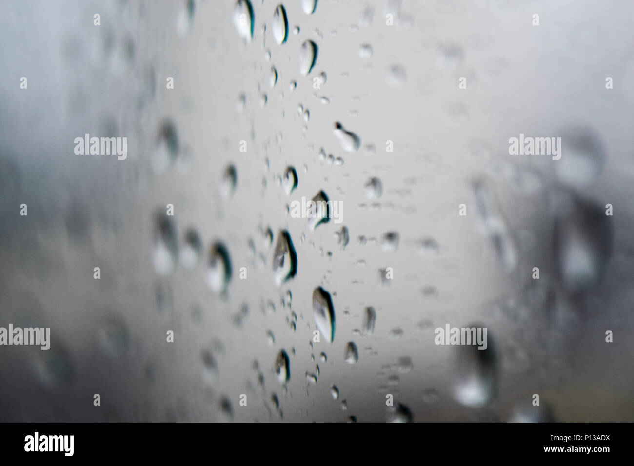 Closeup of raindrops on window in front of city background Stock Photo ...