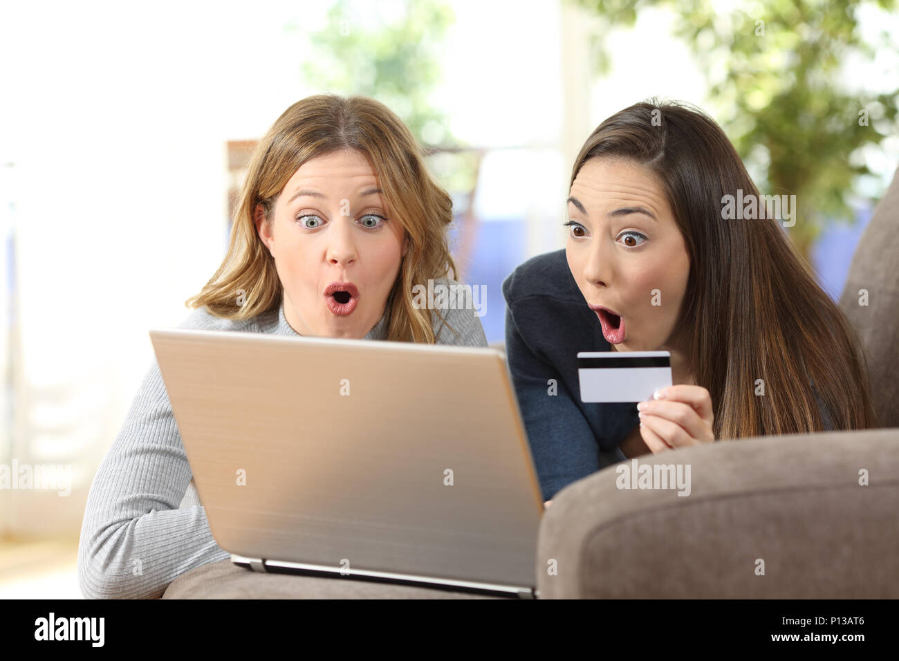 Front view portrait of an amazed friends buying online together sitting ...
