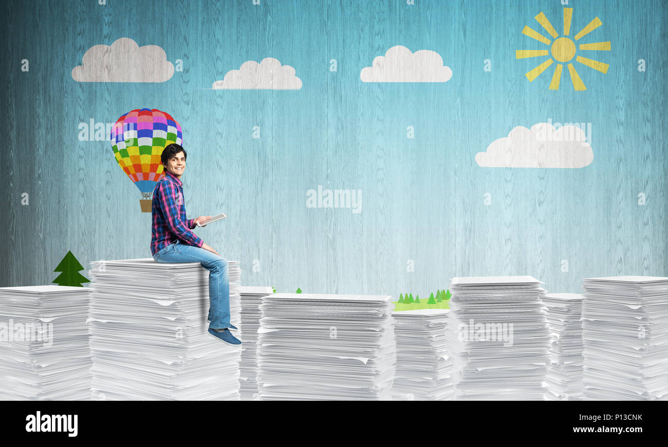 Young man sitting on pile of paper documents Stock Photo - Alamy