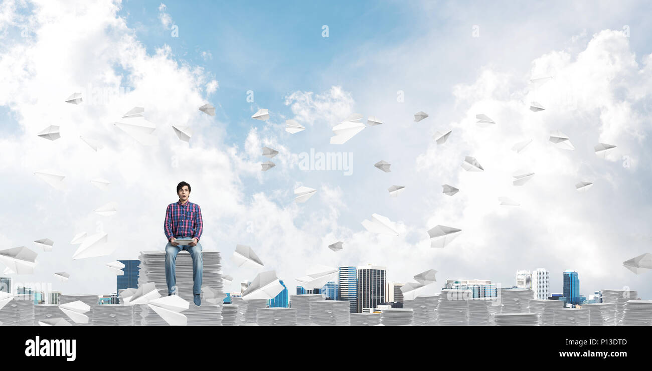 Attractive man sitting on pile of paper documents Stock Photo - Alamy
