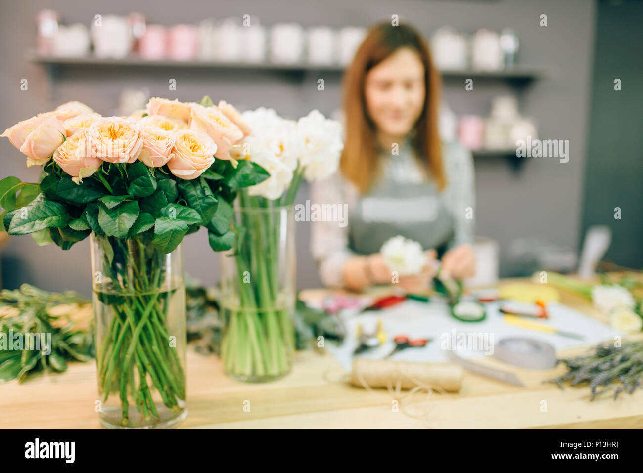 Female florist prepares rose bouquet at workplace. Flower shop, floral ...