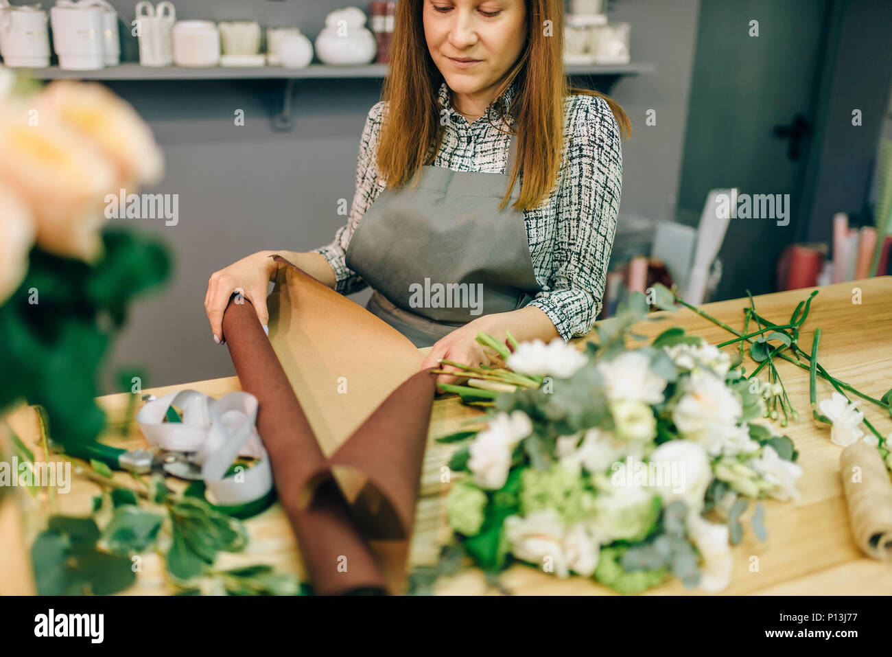 Female florist hands cuts flower composition with pruner, top view ...