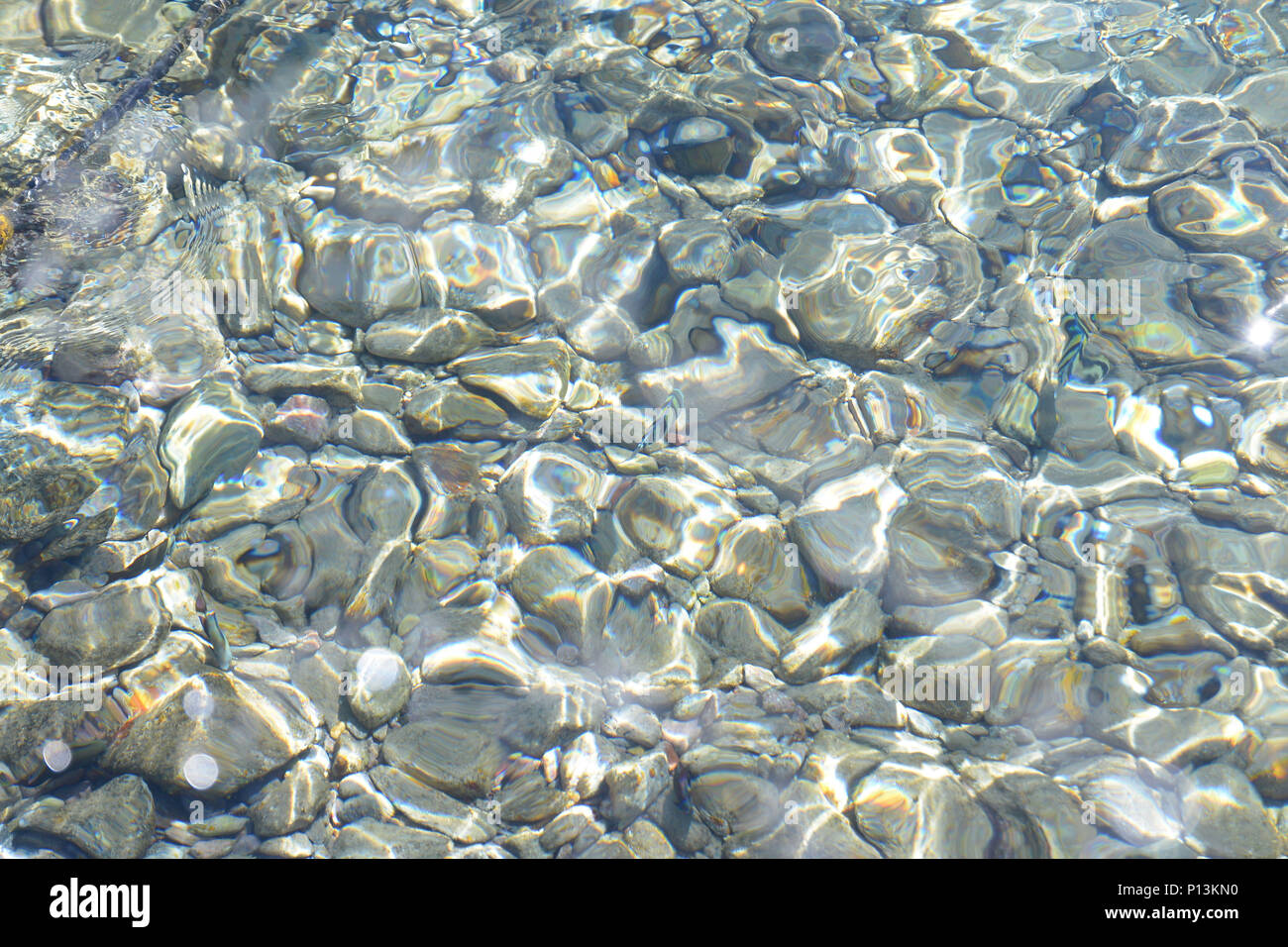 Sea water Pebbles and rocks on beach with pure blue transparent water ...
