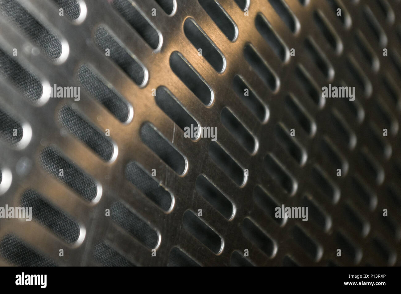 stainless steel grating with oblong holes on black background, close-up ...