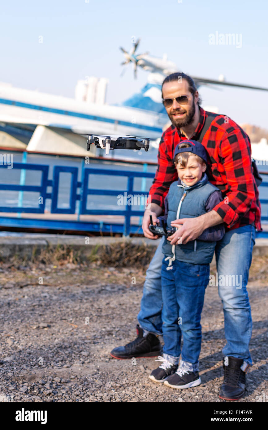 Father and son holding remote control joystick and piloting ...