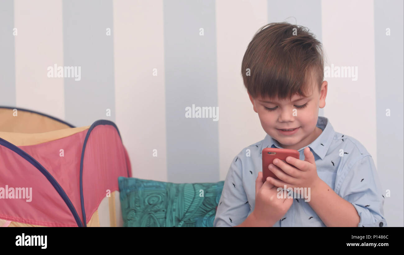Excited little boy reading a message on his phone Stock Photo - Alamy
