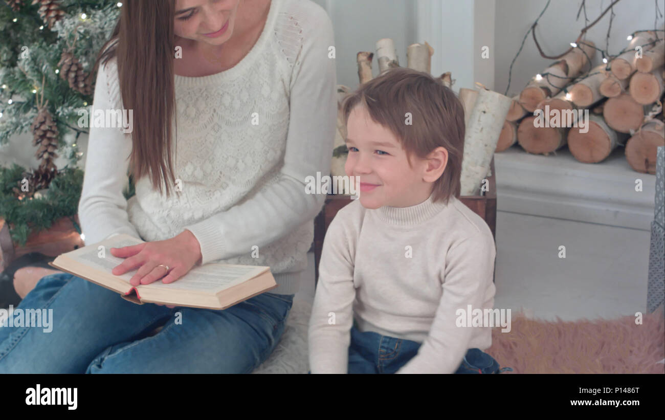 Little boy refusing to read a book together with his mom on Christmas ...
