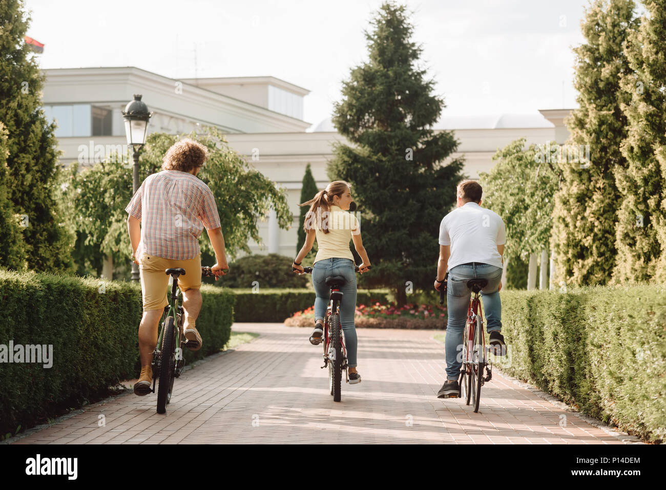 People biking in summer park. Two men and one woman riding bicycles on ...