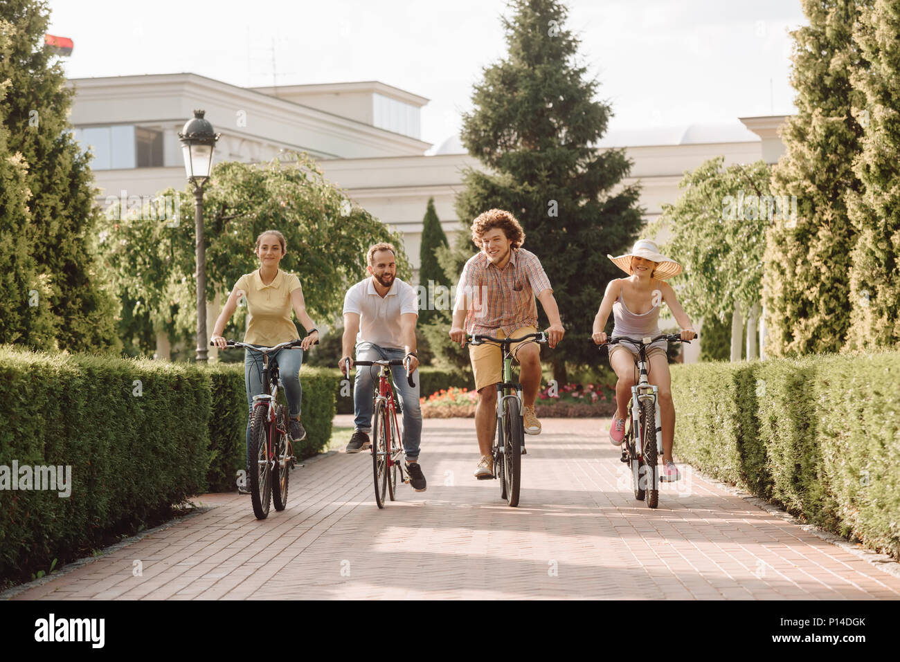 People enjoying bike ride. Four happy students riding bicycles together ...