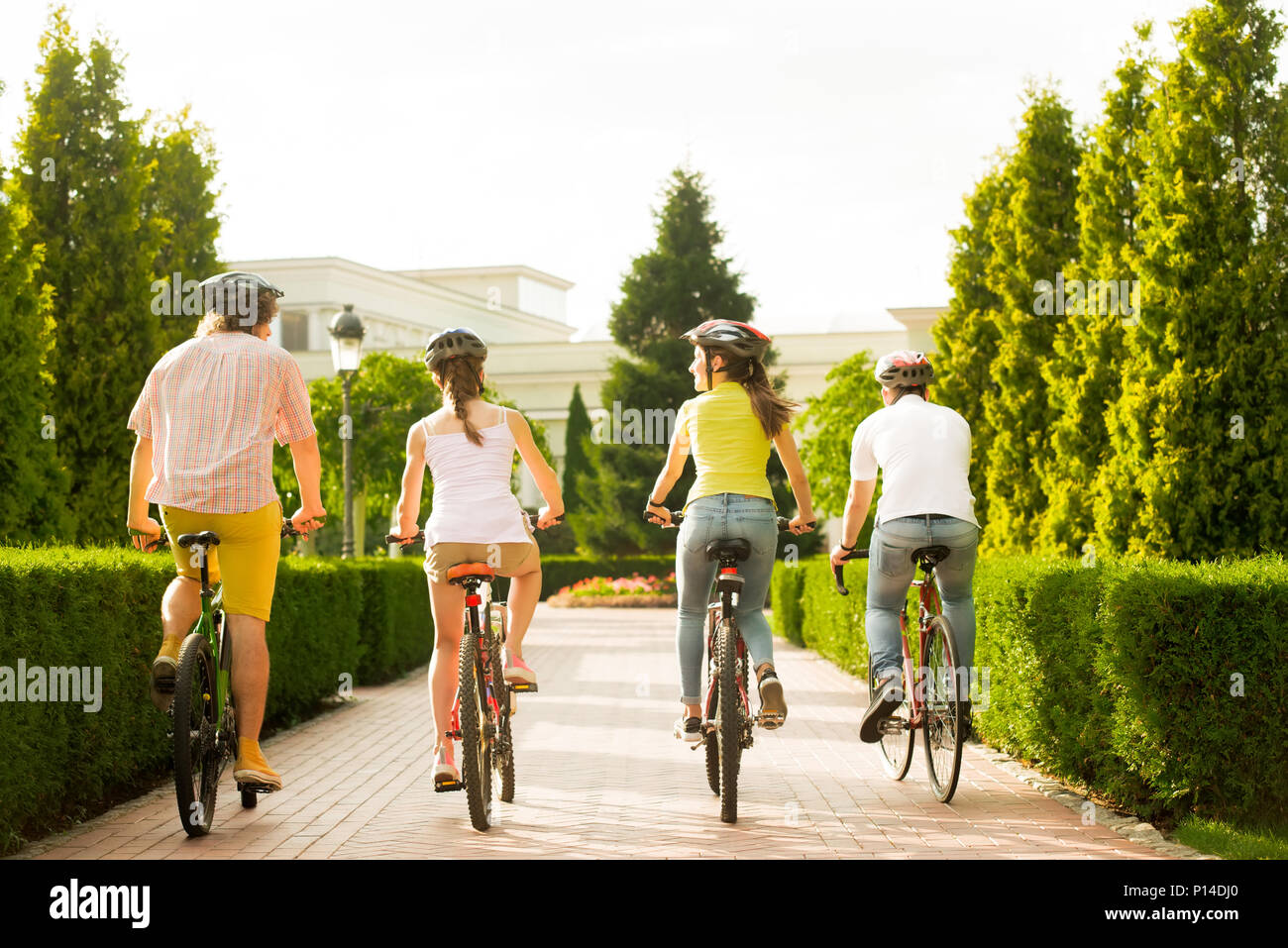 Friends cycling outdoors, back view. Group of young active students ...