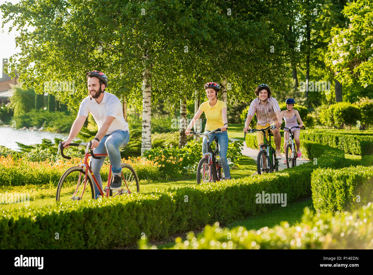 Four cheerful friends cycling outside. Group of young happy persons ...