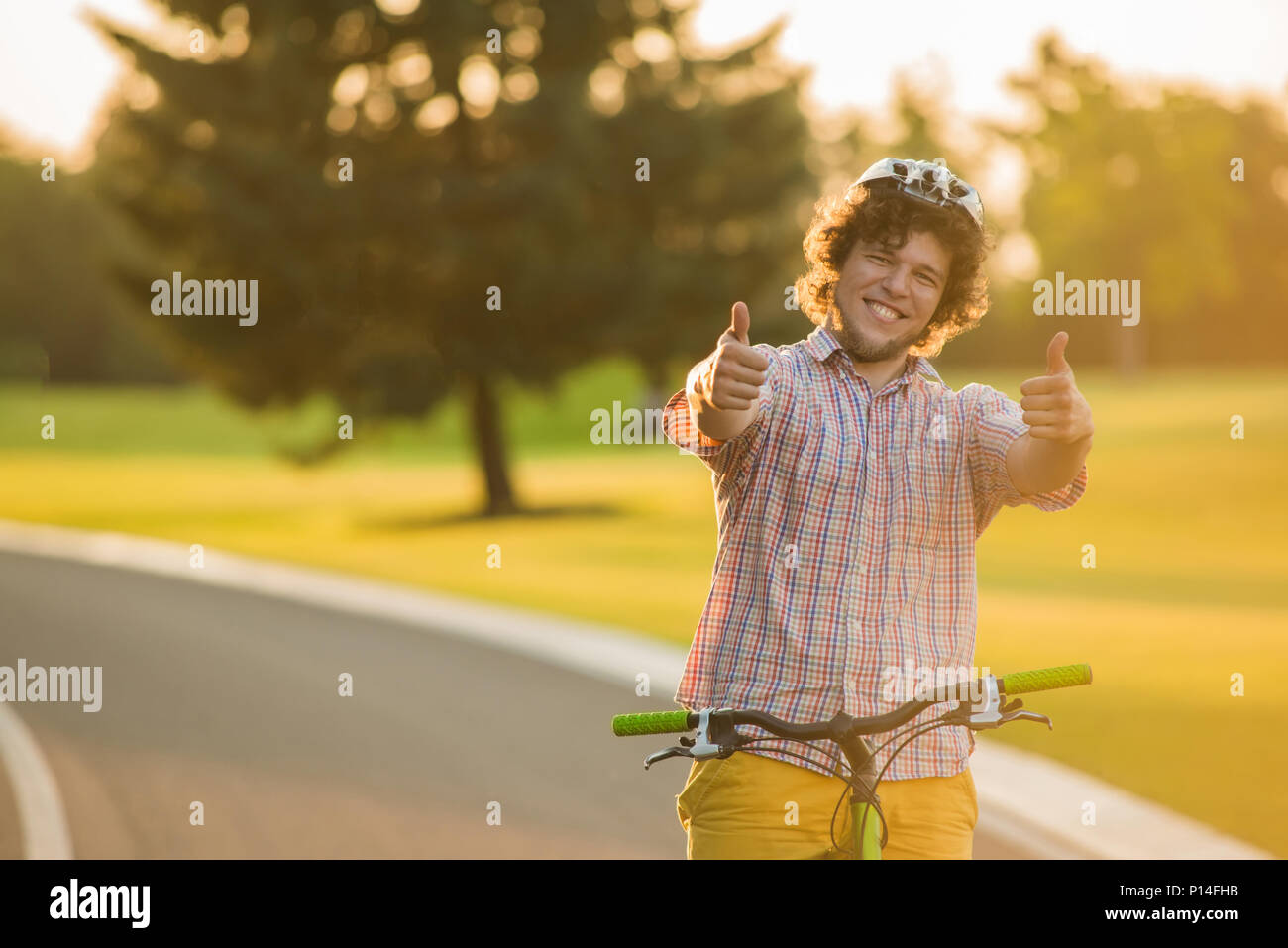 Handsome guy on bike gesturing thumbs up. Portrait of happy male biker ...
