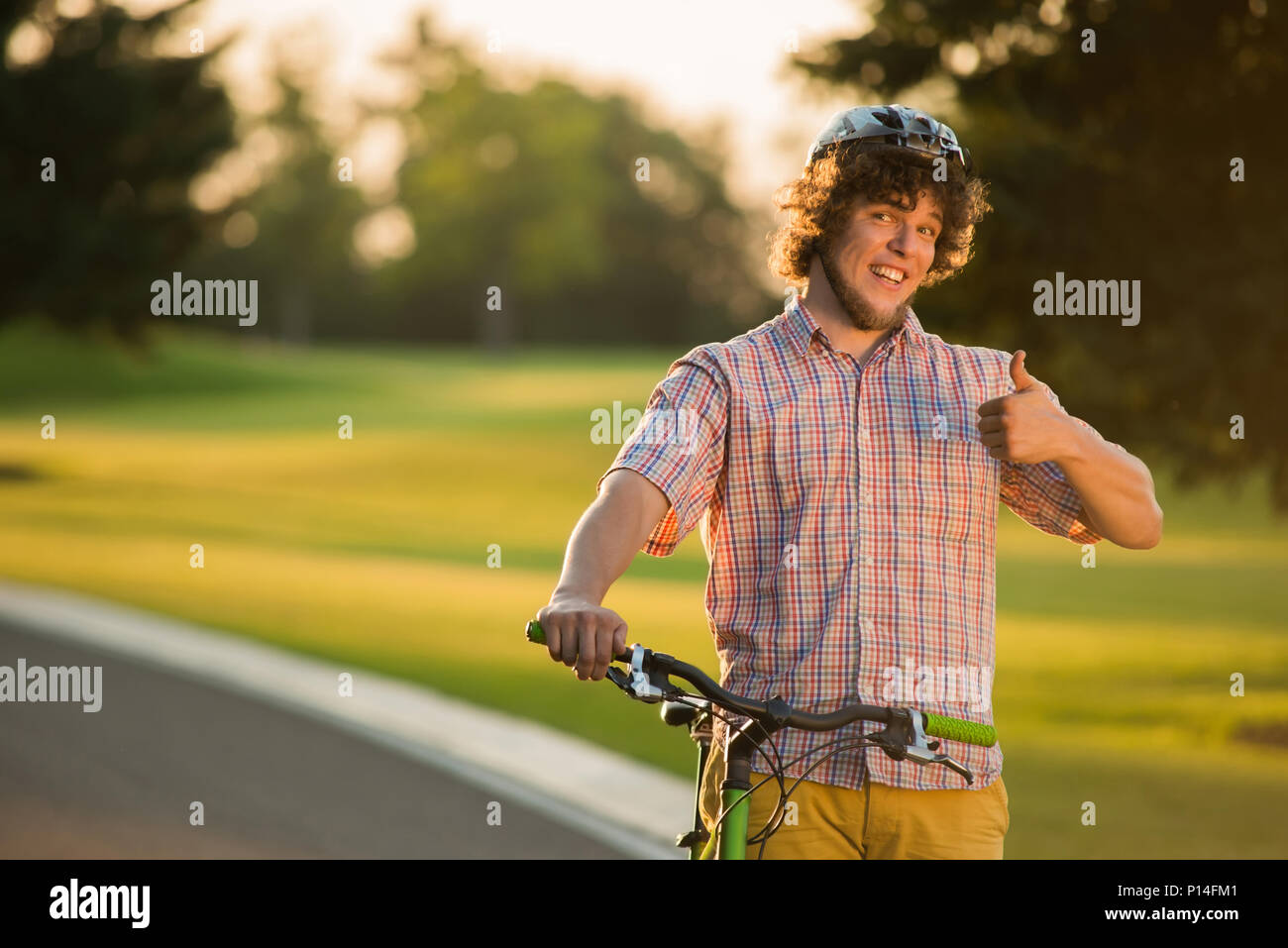 Happy male cyclist giving thumb up sign. Portrait of cheerful student ...