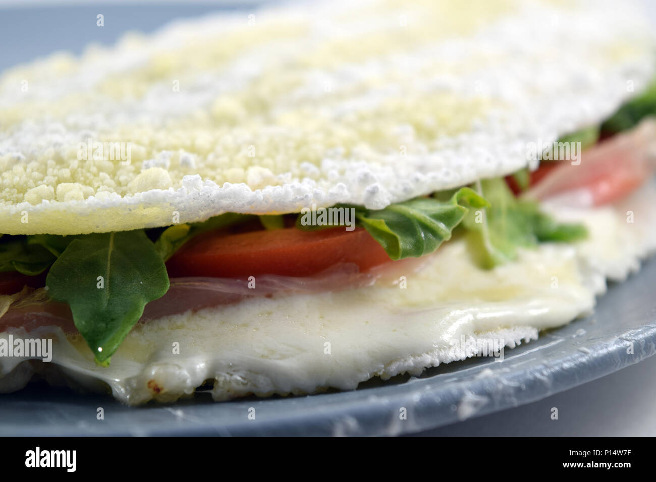 Brazilian tapioca on a plate filled with cheese, tomato, arugula, and ...