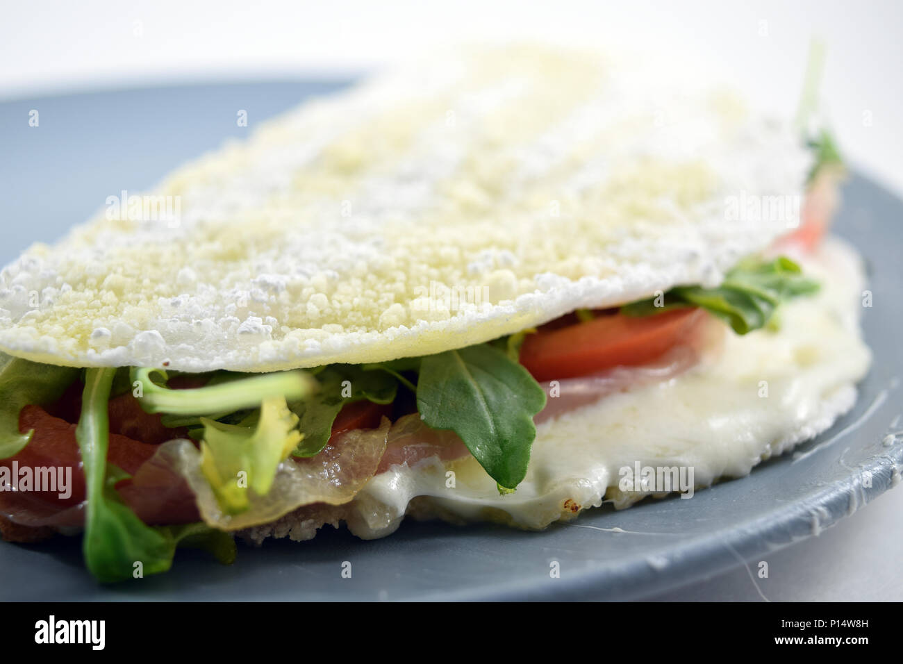Brazilian tapioca on a plate filled with cheese, tomato, arugula, and ...