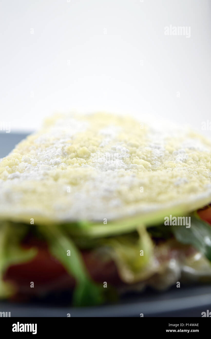 Brazilian tapioca on a plate filled with cheese, tomato, arugula, and ...
