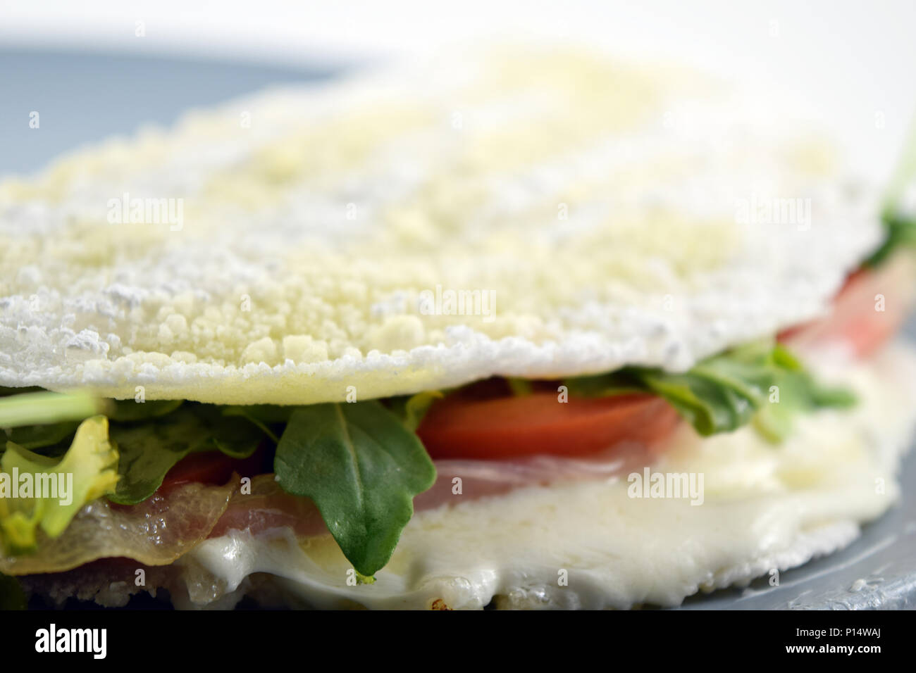 Brazilian tapioca on a plate filled with cheese, tomato, arugula, and ...