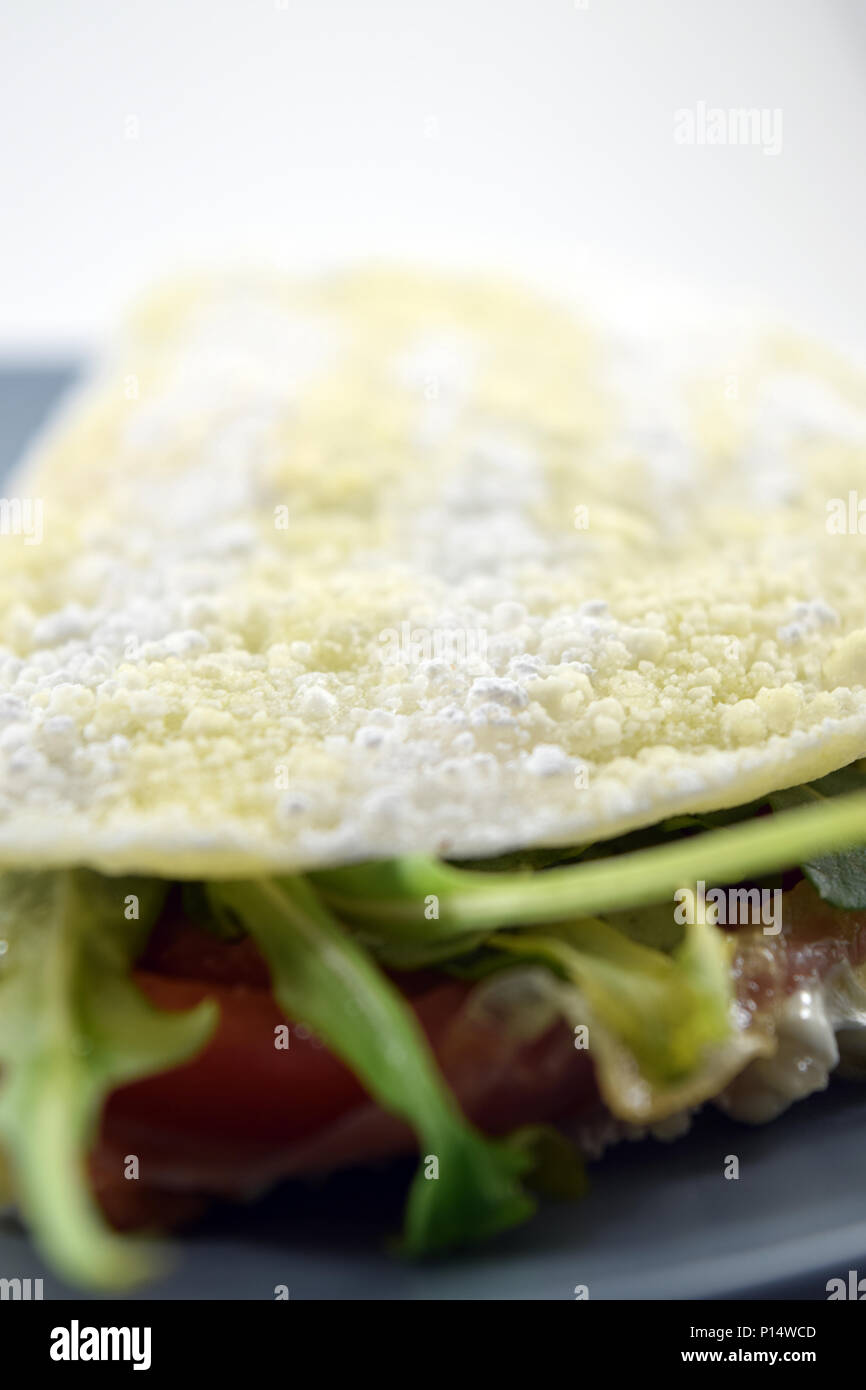 Brazilian tapioca on a plate filled with cheese, tomato, arugula, and ...