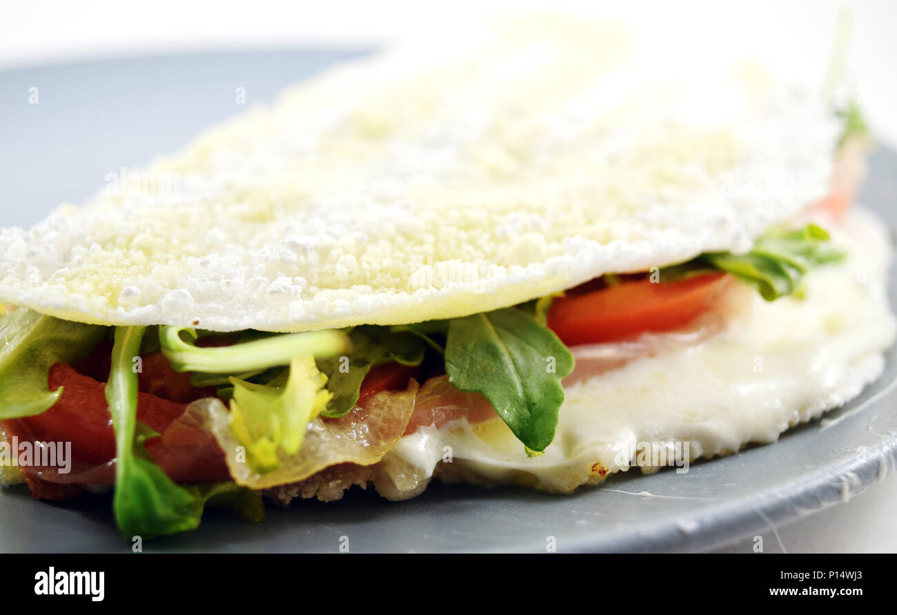 Brazilian tapioca on a plate filled with cheese, tomato, arugula, and ...