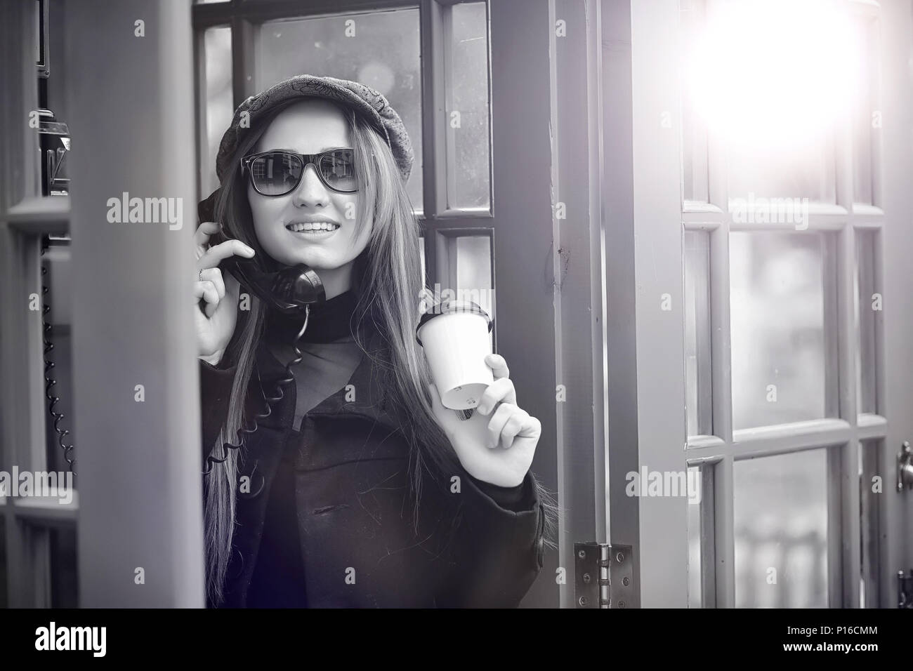 Beautiful young girl in a phone booth. The girl is talking on the phone ...