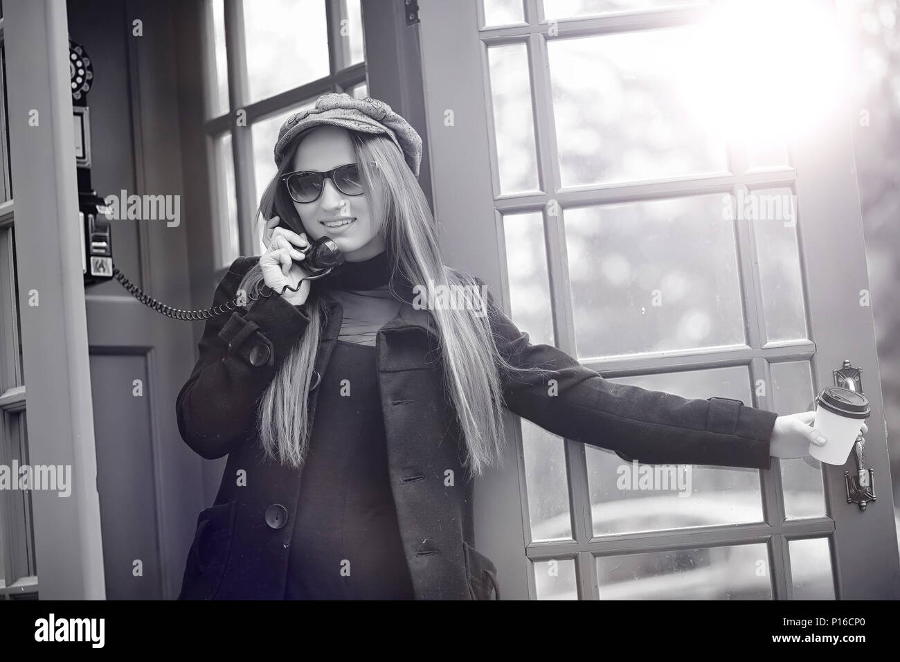 Beautiful young girl in a phone booth. The girl is talking on the phone ...