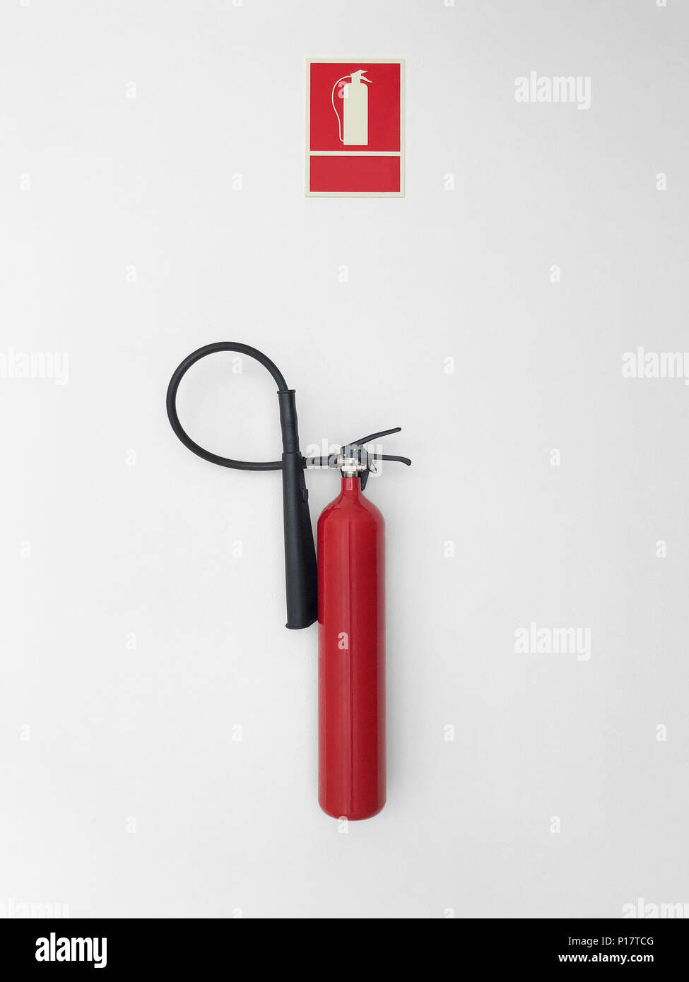 Fire extinguisher with sign alarm on a white wall. Warning Stock Photo ...