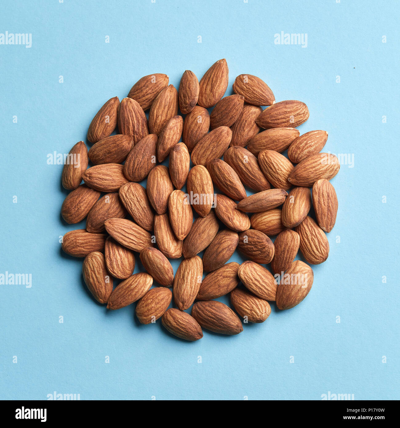 A circle of almonds on a blue paper background. Delicious healthy food ...