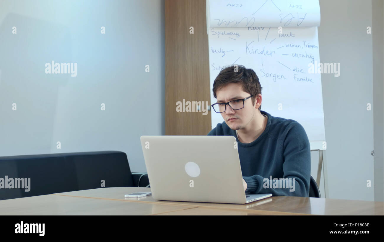 Concentrated young man using laptop in class room Stock Photo - Alamy