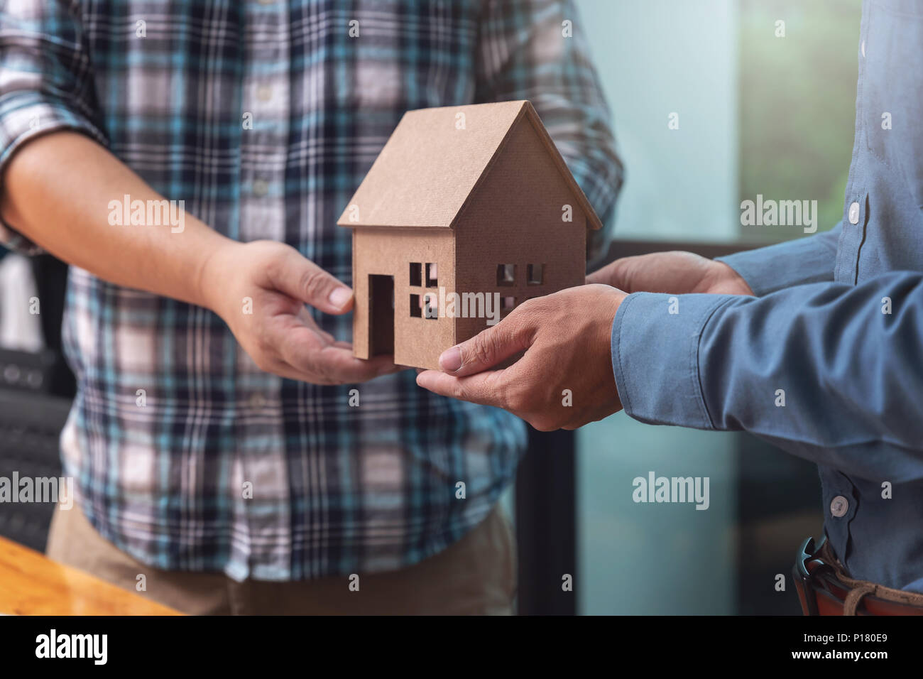 Real estate agent handing over a house model with his client after ...