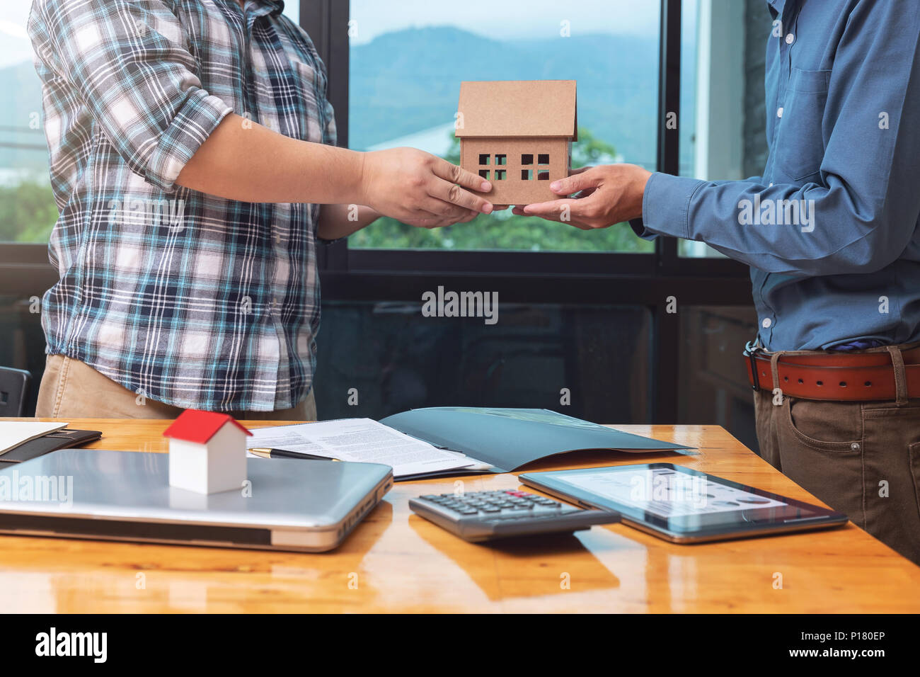 Real estate agent handing over a house model with his client after ...