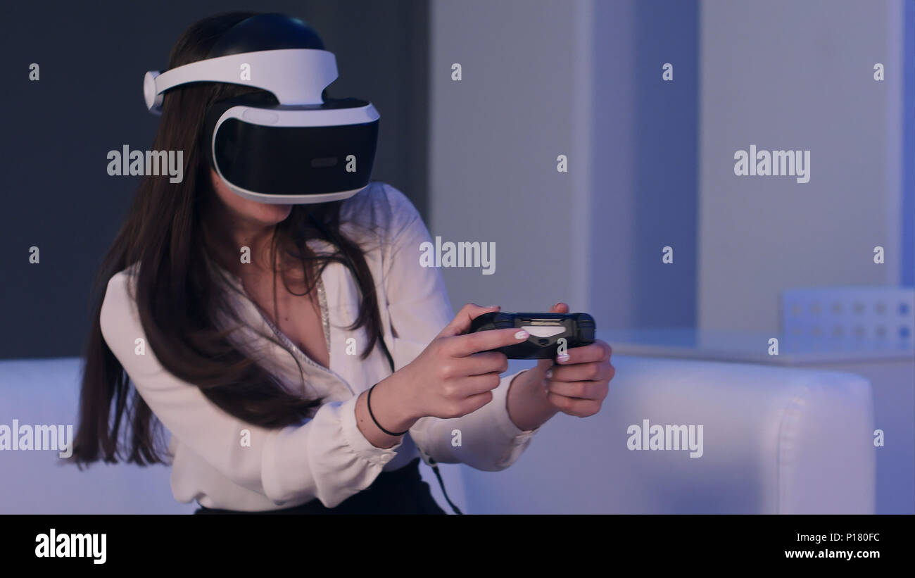 Woman wearing virtual reality device and playing video game with ...