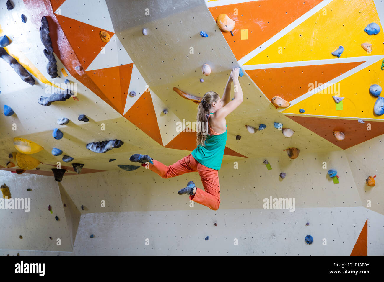 Young athletic woman jumping on handhold in bouldering gym Stock Photo ...