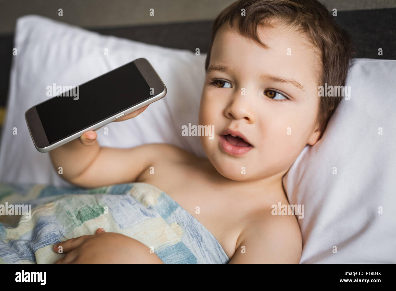 Boy holding mobile phone lying hi-res stock photography and images - Alamy