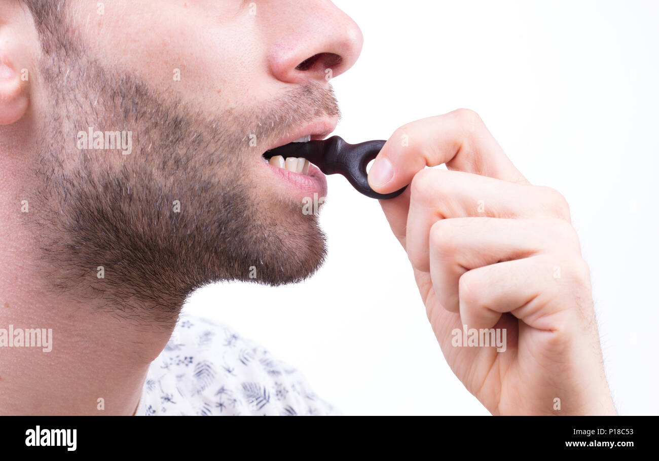 Man eating typicaly dutch candy called 'Dropsleutel' (candy key ...