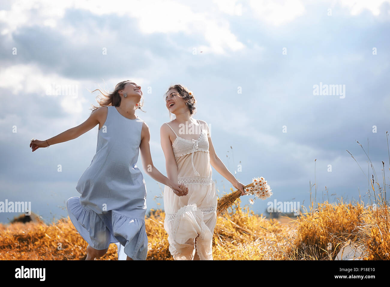Two beautiful girls in dresses in autumn field have fun Stock Photo - Alamy