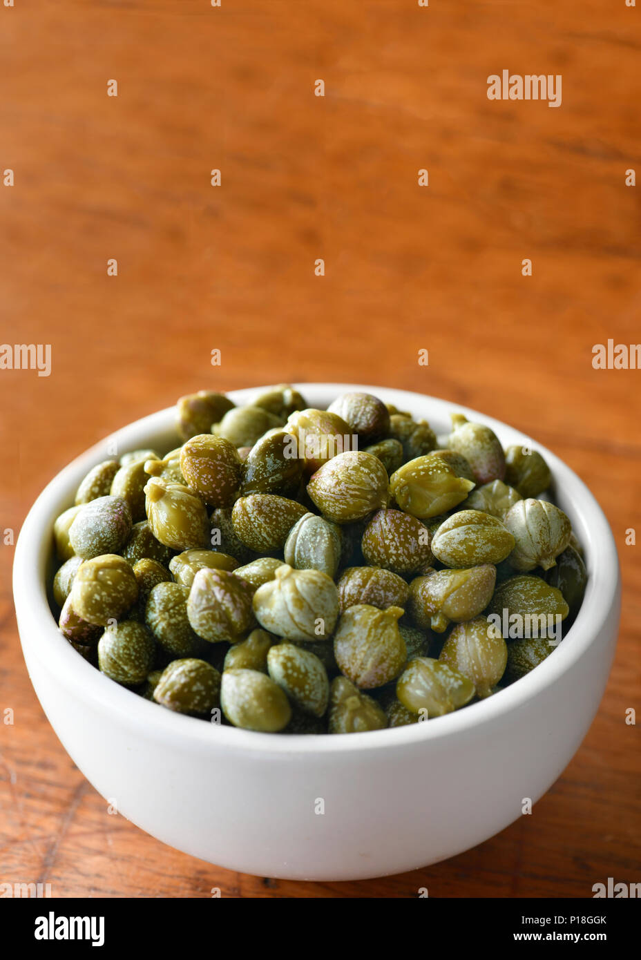 organic capers , capparis spinosa in a white round bowl macro shot in a ...
