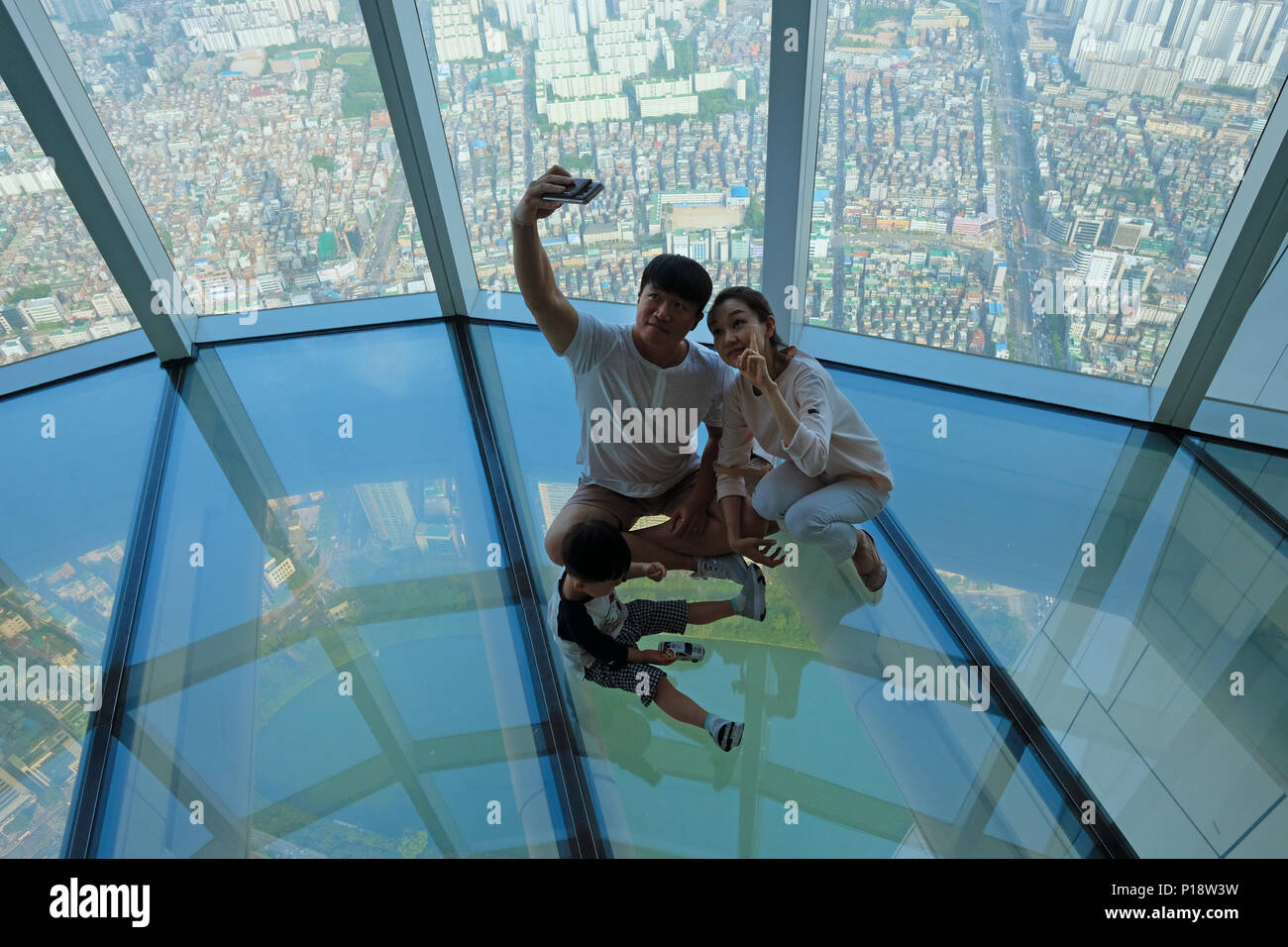 A Korean family taking selfie photo at the glass floor observatory of Lotte World Tower a 123 ...
