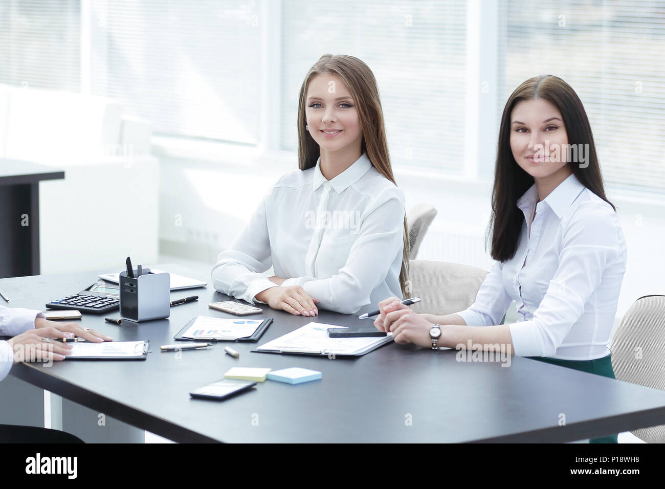 three young employees sitting behind a Desk Stock Photo - Alamy