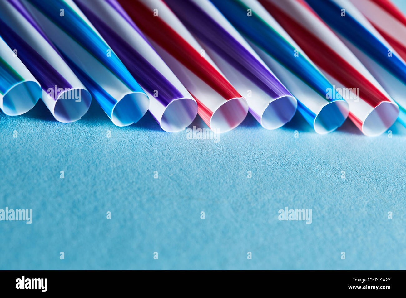 Blue, purple and red plastic straws on a blue paper background. Copy ...