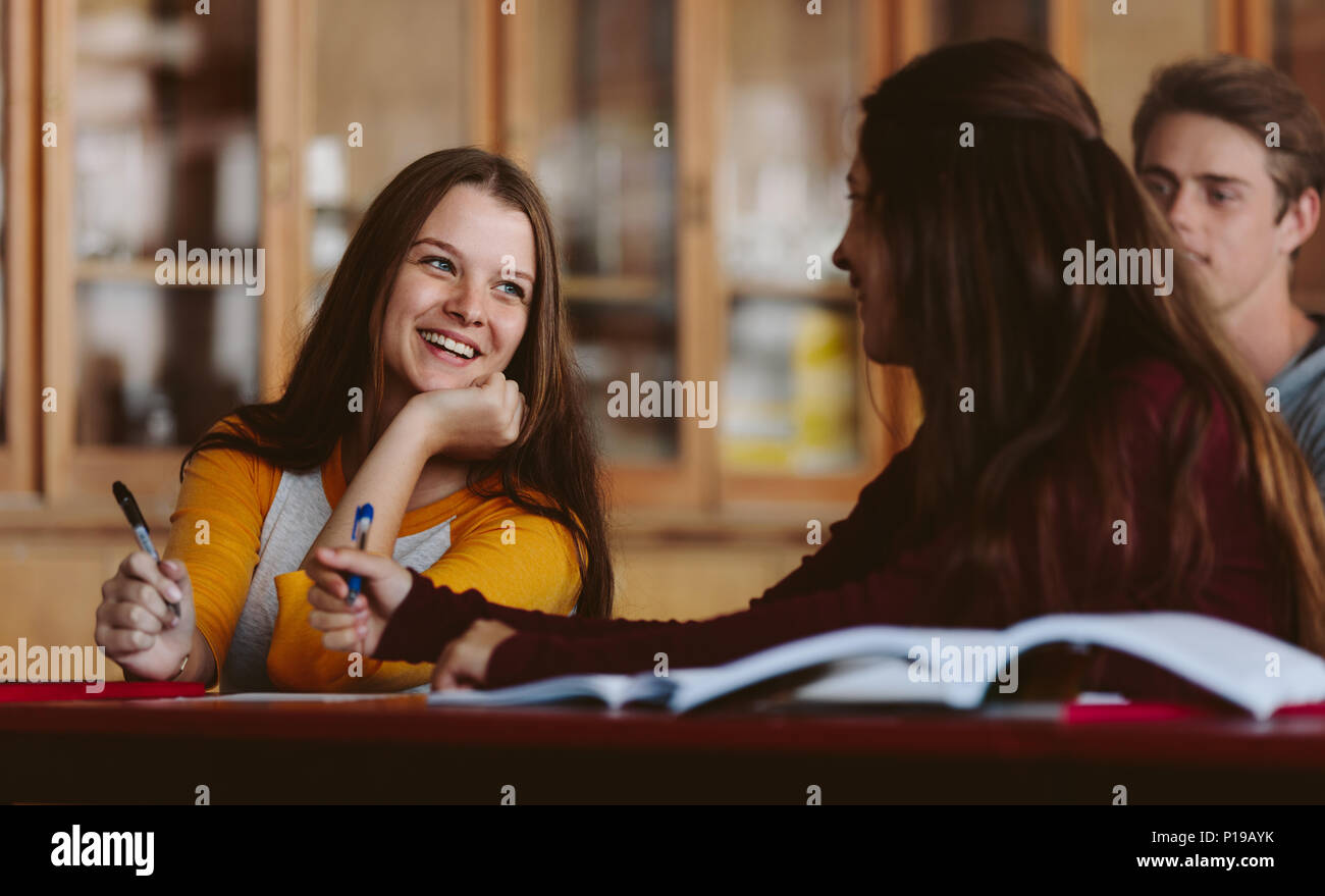 Smiling young woman sitting in the classroom and talking with ...