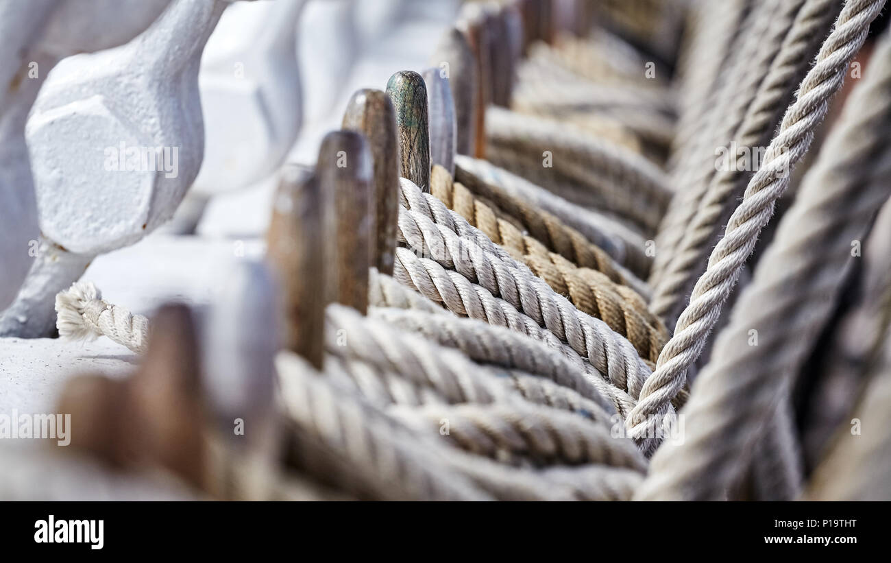 Old sailing ship rigging with belaying pins and ropes, shallow depth of ...