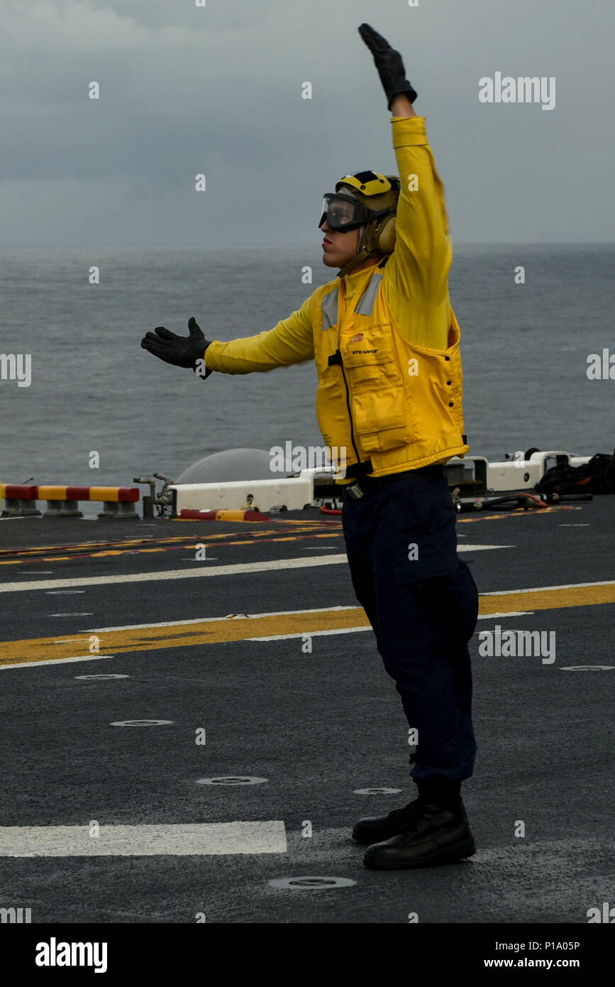 A seaman signals to an MH-60 Seahawk helicopter during a vertical ...